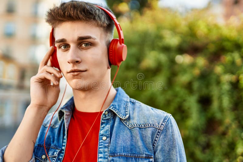 Young Caucasian Guy Wearing Headphones Listening To Music At The City