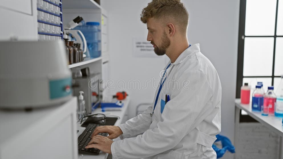 A Young, Caucasian Male Scientist with a Beard Works at a Computer ...