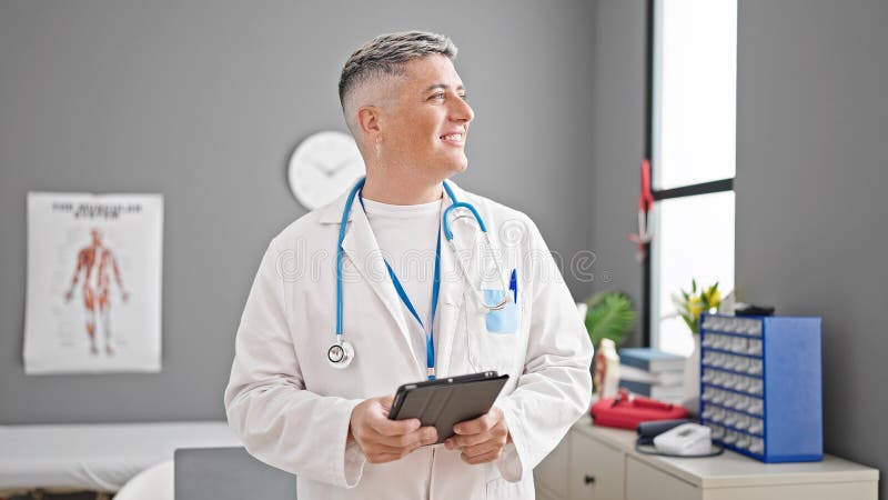 Young Caucasian Man Doctor Using Touchpad Smiling at the Clinic Stock ...