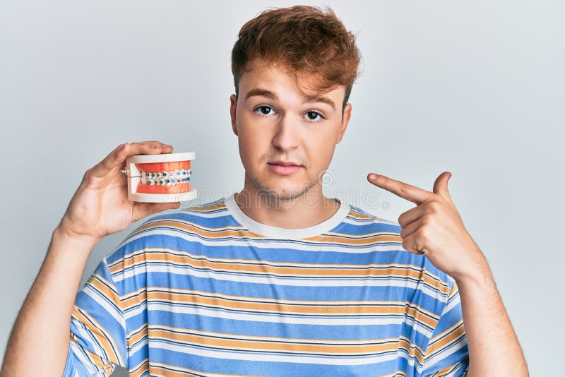 Young Caucasian Man Holding Denture Relaxed with Serious Expression on ...