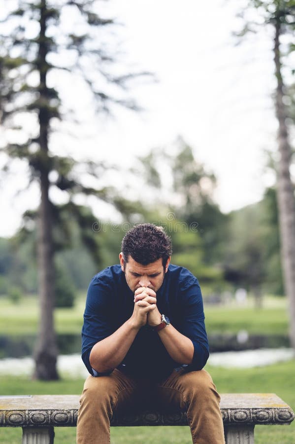 Young Caucasian Man Praying while Sitting on a Bench Stock Image ...