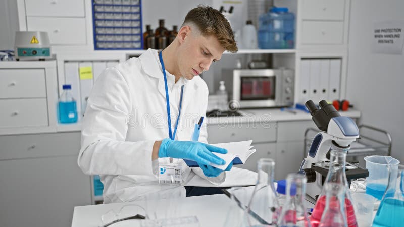 Young Caucasian Man Scientist Reading Book Thinking at Laboratory Stock ...