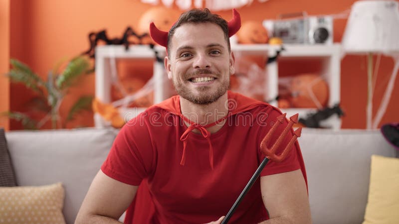 Young Caucasian Man Smiling Wearing Devil Costume Sitting on the Sofa ...