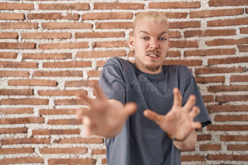 Young Caucasian Man Standing Over Bricks Wall Afraid and Terrified with ...