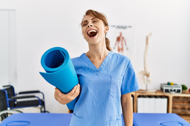 Young Caucasian Physio Therapist Girl Smiling Happy Holding Yoga Mat At
