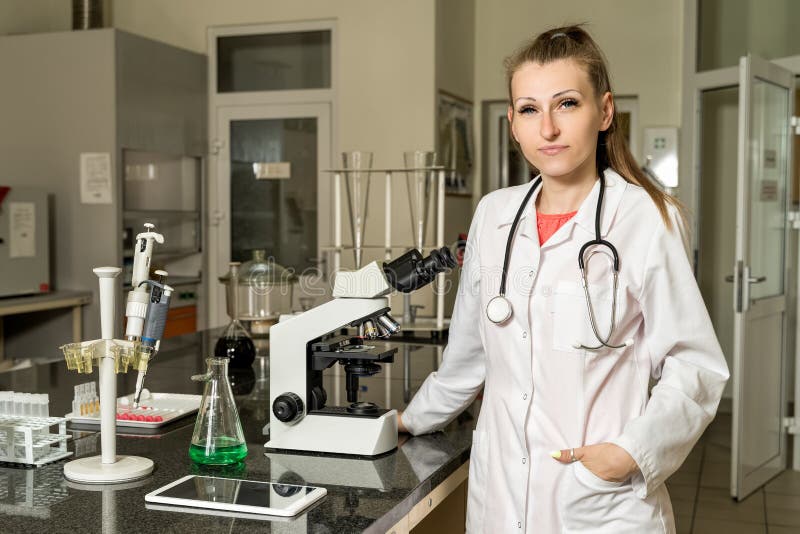 Young Female Laboratory Technician Standing Next To Compound Microscope ...
