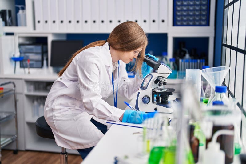 Young Caucasian Woman Scientist Using Microscope Write on Document at ...