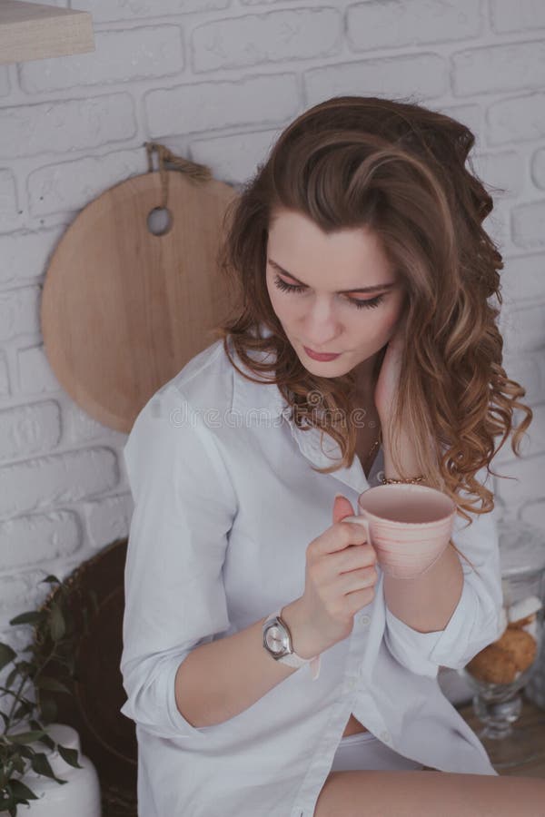 Young Woman Sitting on the Table with a Cup of Coffee or Tea in the ...