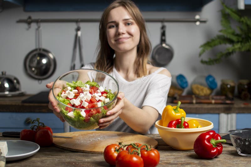 Young Girl Prepares A Vegetarian Salad In The Kitchen Holds A Ready