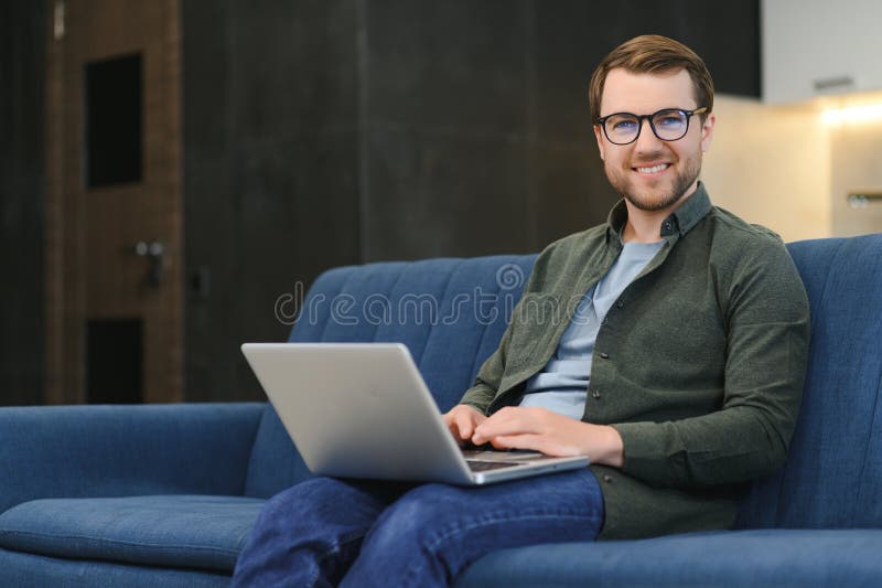 Young Cheerful Man Sitting on Sofa with Laptop Stock Image - Image of ...