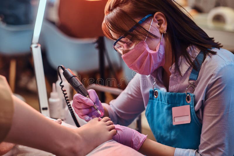 Young Cheerful Nail Master is Working on Client`s Toe Nails at Her ...