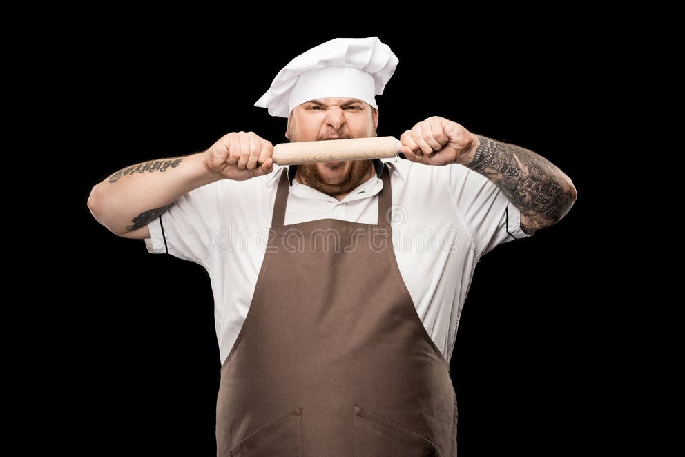 Young Chef in Hat and Apron Biting Rolling Pin Isolated on Black Stock ...