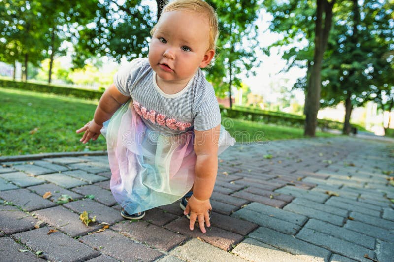 Young Child Crawling on Paved Pathway Surrounded by Lush Green Trees in ...