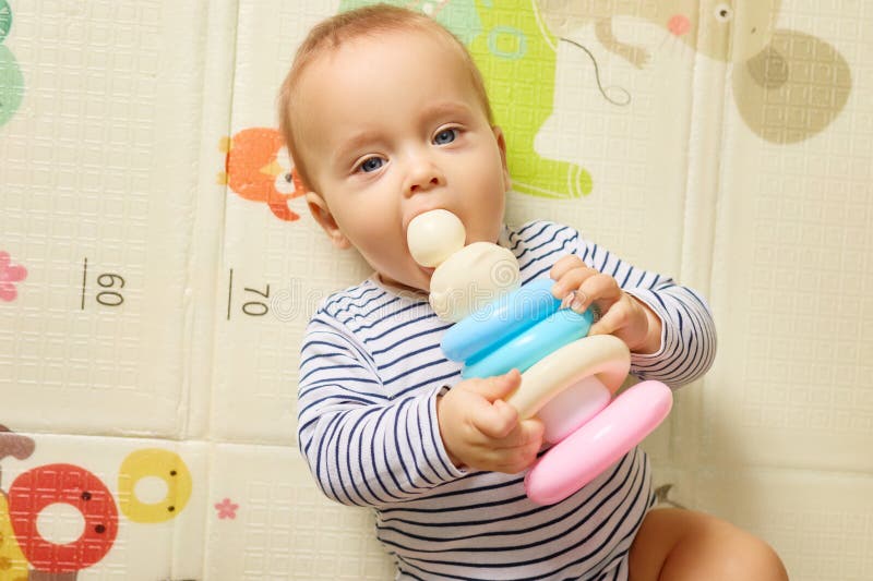 A Young Child Lies on a Patterned Mat, Engaged with a Vibrant Stacking ...