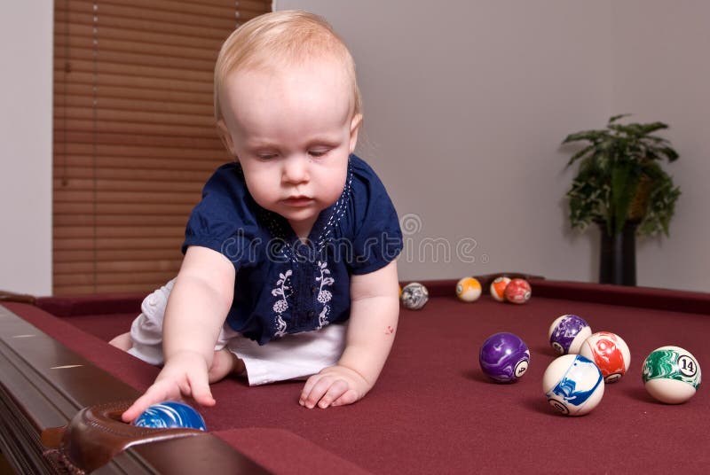 Young Child Sitting on a Billiard Table Dropping a Ball in a Pocket ...