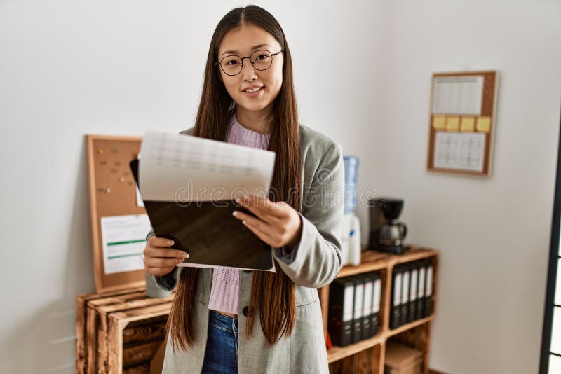 Young Chinese Businesswoman Reading Document on Clipboard at the Office ...