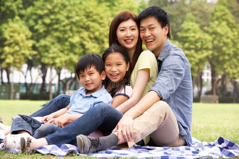 Young Chinese Family Relaxing In Park Together Royalty Free Stock Photo ...