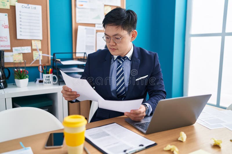 Young Chinese Man Business Worker Using Laptop Reading Document at ... Young Chinese Man Business Worker Using Laptop Reading Document at ...