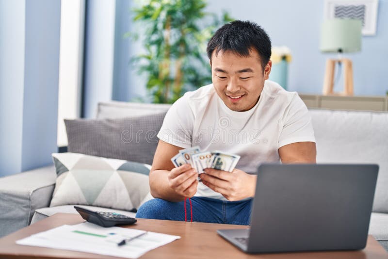 Young Chinese Man Counting Dollars Sitting on Sofa at Home Stock Image ...
