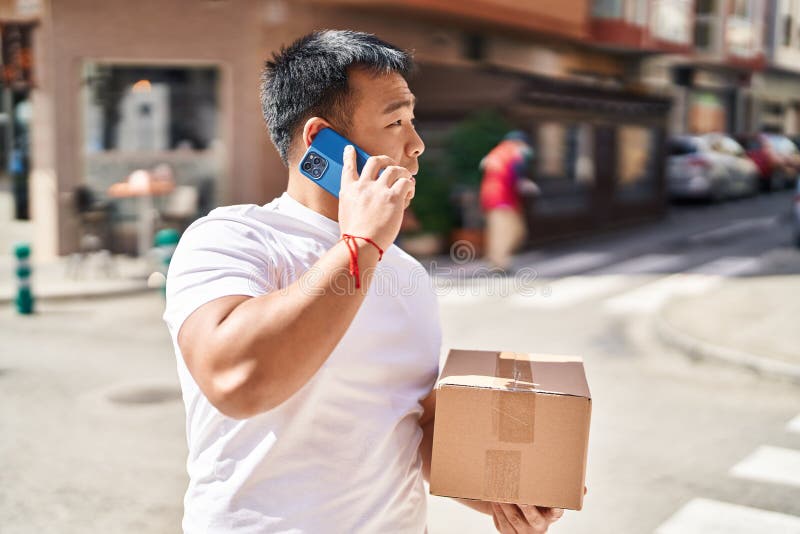 Young Chinese Man Courier Talking on the Smartphone Holding Package at ...