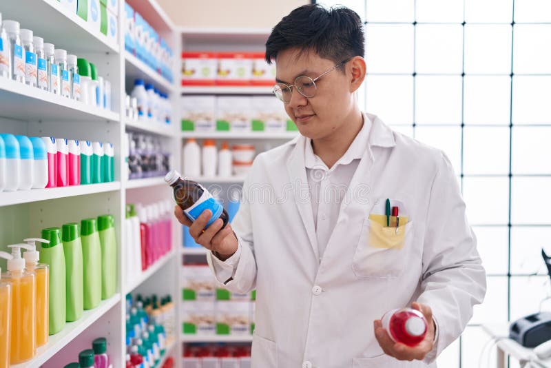 Young Chinese Man Pharmacist Holding Medication Bottles at Pharmacy ...