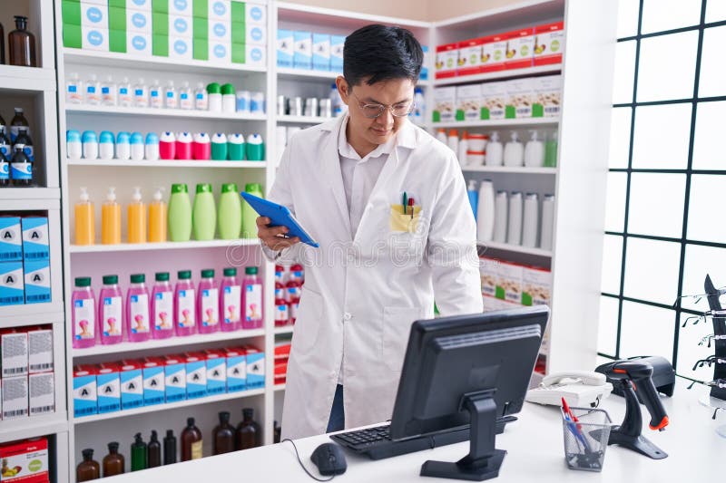 Young Chinese Man Pharmacist Using Touchpad and Computer Working at ...