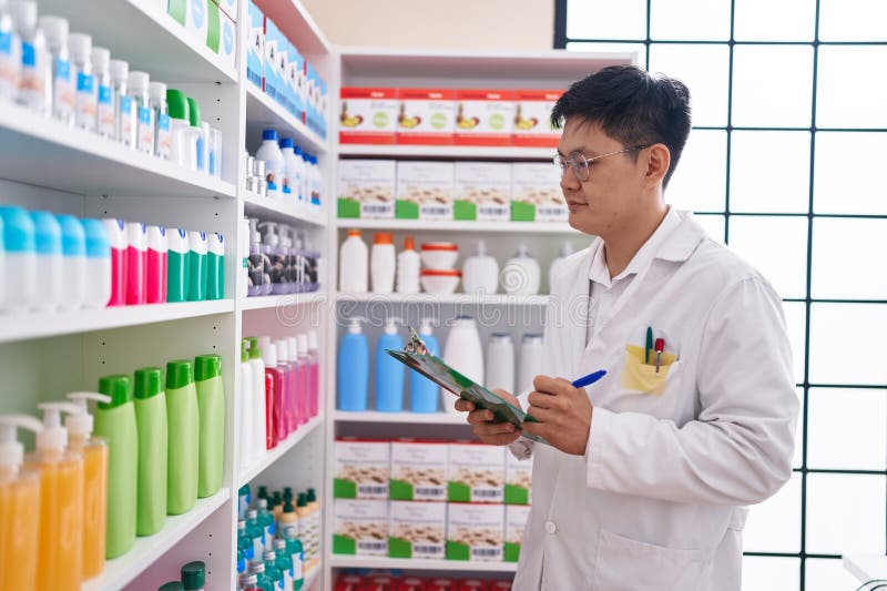Young Chinese Man Pharmacist Writing on Document at Pharmacy Stock ...