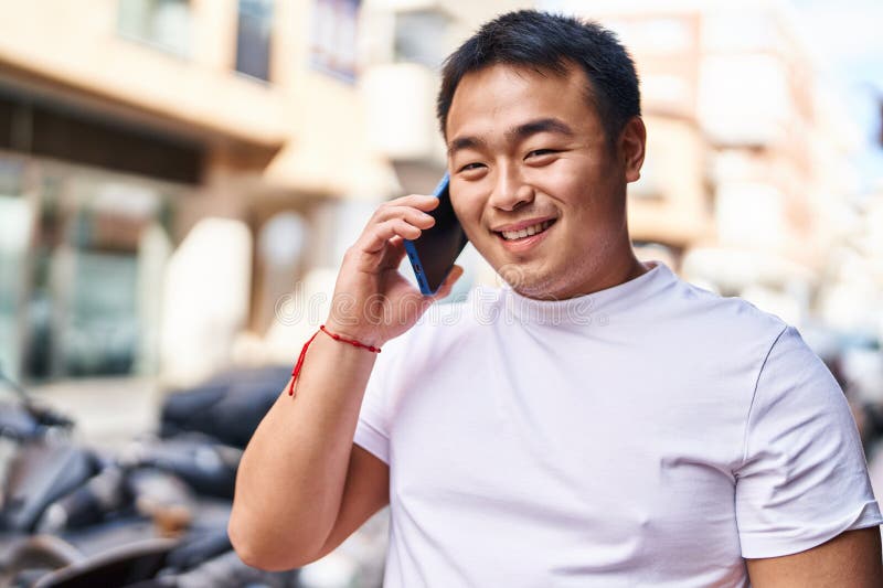 Young Chinese Man Smiling Confident Talking on the Smartphone at Street ...