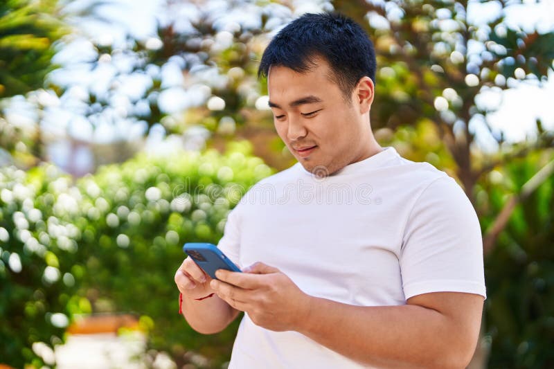 Young Chinese Man Smiling Confident Using Smartphone at Park Stock ...
