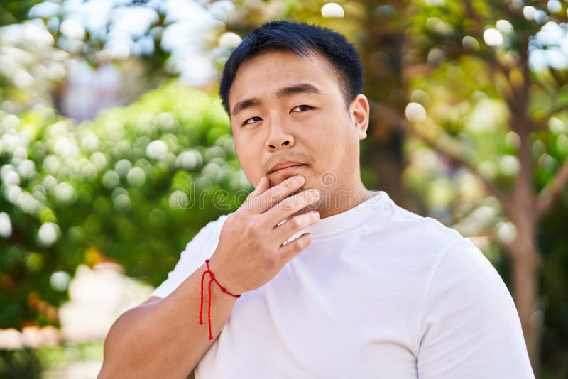 Young Chinese Man Standing with Doubt Expression at Park Stock Photo ...
