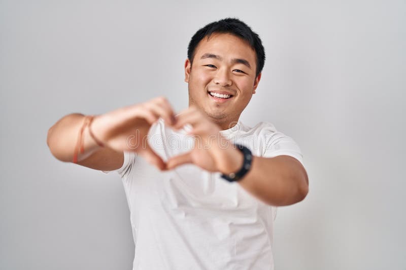 Young Chinese Man Standing Over White Background Smiling in Love Doing ... Young Chinese Man Standing Over White Background Smiling in Love Doing ...
