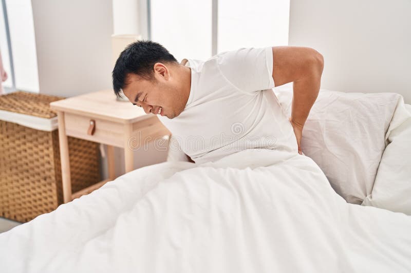 Young Chinese Man Suffering for Backache Sitting on Bed at Bedroom ...