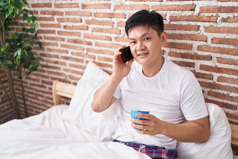 Young Chinese Man Talking on Smartphone Drinking Coffee at Bedroom ...
