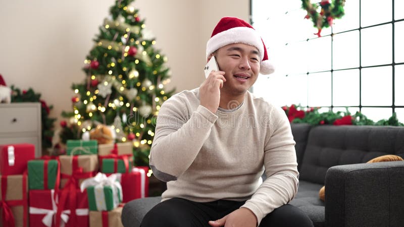 Young Chinese Man Talking on Smartphone Sitting on Sofa by Christmas ...