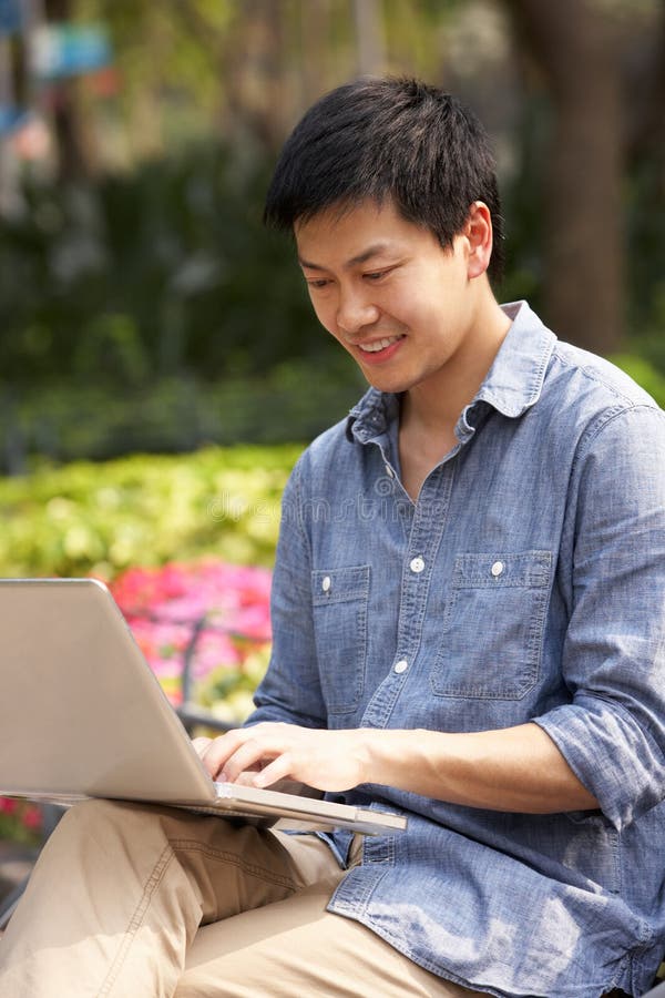 Young Chinese Man Using Laptop Whilst Relaxing Stock Image - Image of ...