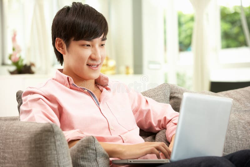 Young Chinese Man Using Laptop Whilst Relaxing Stock Photo - Image of ...