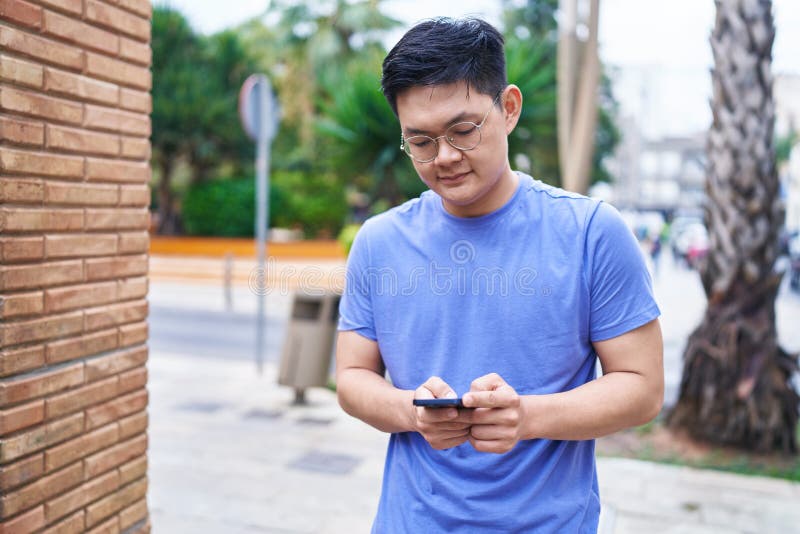 Young Chinese Man Using Smartphone with Serious Expression at Street ...