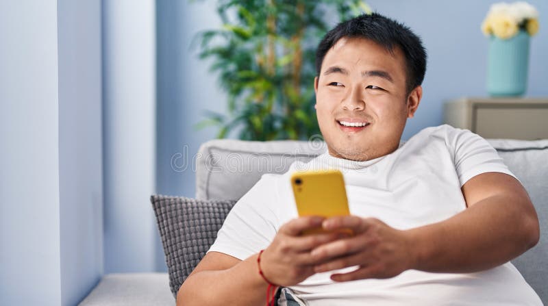 Young Chinese Man Using Smartphone Sitting on Sofa at Home Stock Image ...