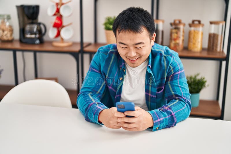 Young Chinese Man Using Smartphone Sitting on Table at Home Stock Image ...