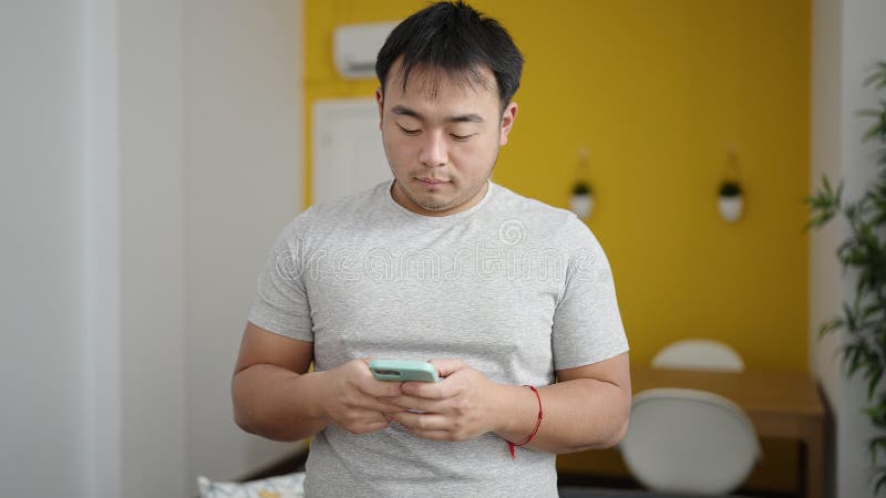 Young Chinese Man Using Smartphone Standing at Home Stock Photo - Image ...