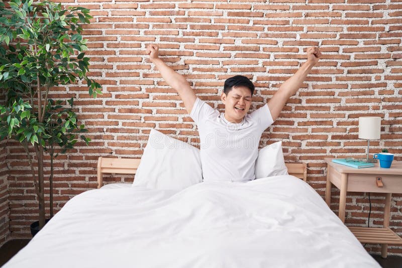 Young Chinese Man Waking Up Stretching Arms at Bedroom Stock Image ...
