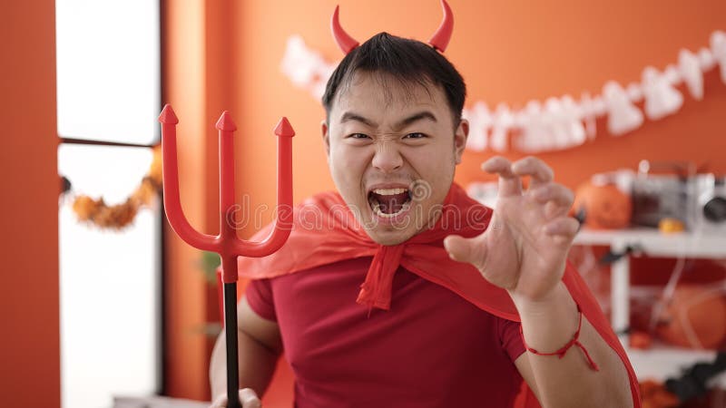Young Chinese Man Wearing Devil Costume Doing Scare Gesture at Home ...