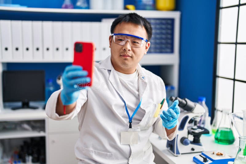 Young Chinese Man Wearing Scientist Uniform Having Video Call at ... Young Chinese Man Wearing Scientist Uniform Having Video Call at ...