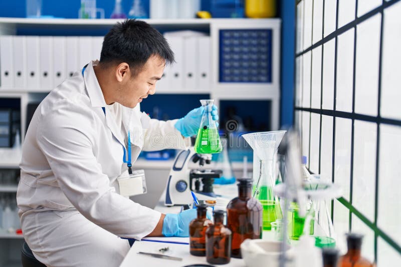 Young Chinese Man Wearing Scientist Uniform Measuring Liquid at ...