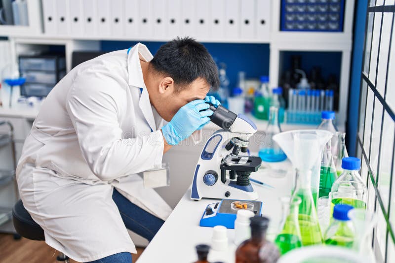Young Chinese Man Wearing Scientist Uniform Using Microscope at ...