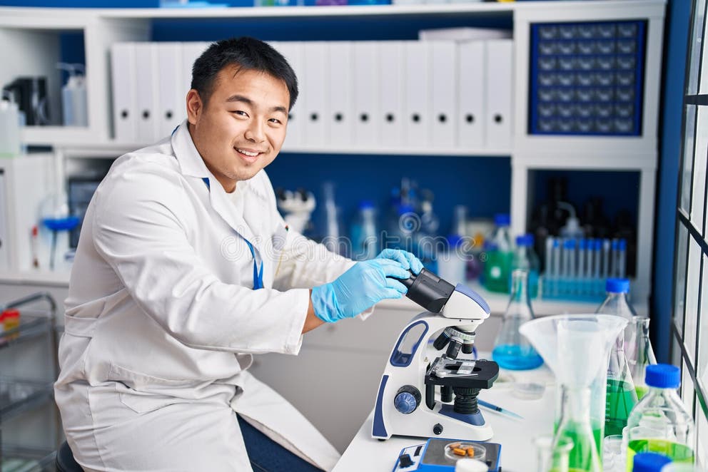 Young Chinese Man Wearing Scientist Uniform Using Microscope at ...