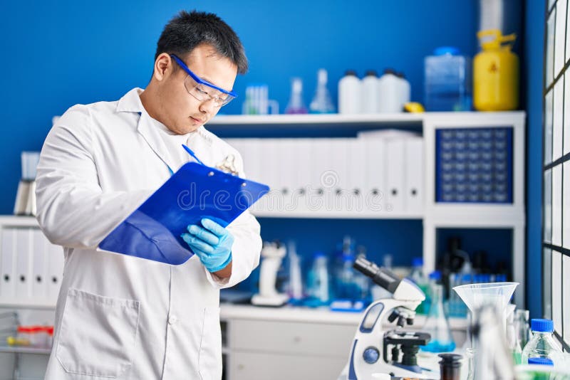Young Chinese Man Wearing Scientist Uniform Writing on Clipboard at ... Young Chinese Man Wearing Scientist Uniform Writing on Clipboard at ...