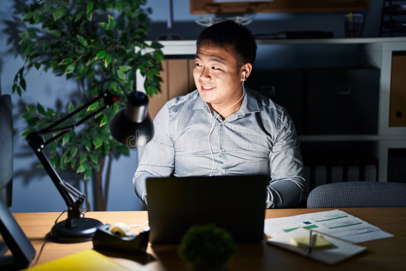 Young Chinese Man Working Using Computer Laptop at Night Looking Away ...