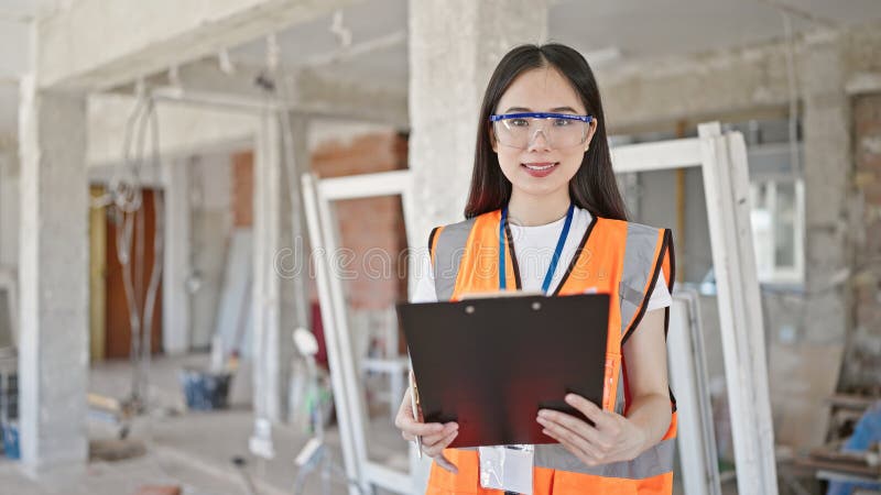 Young Chinese Woman Builder Smiling Confident Reading Document at ...