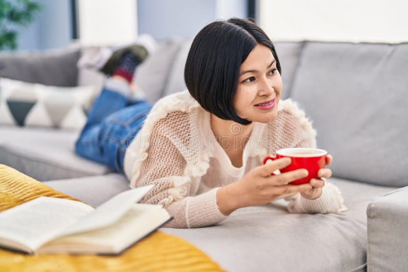Young Chinese Woman Drinking Coffee Lying on Sofa at Home Stock Photo ...